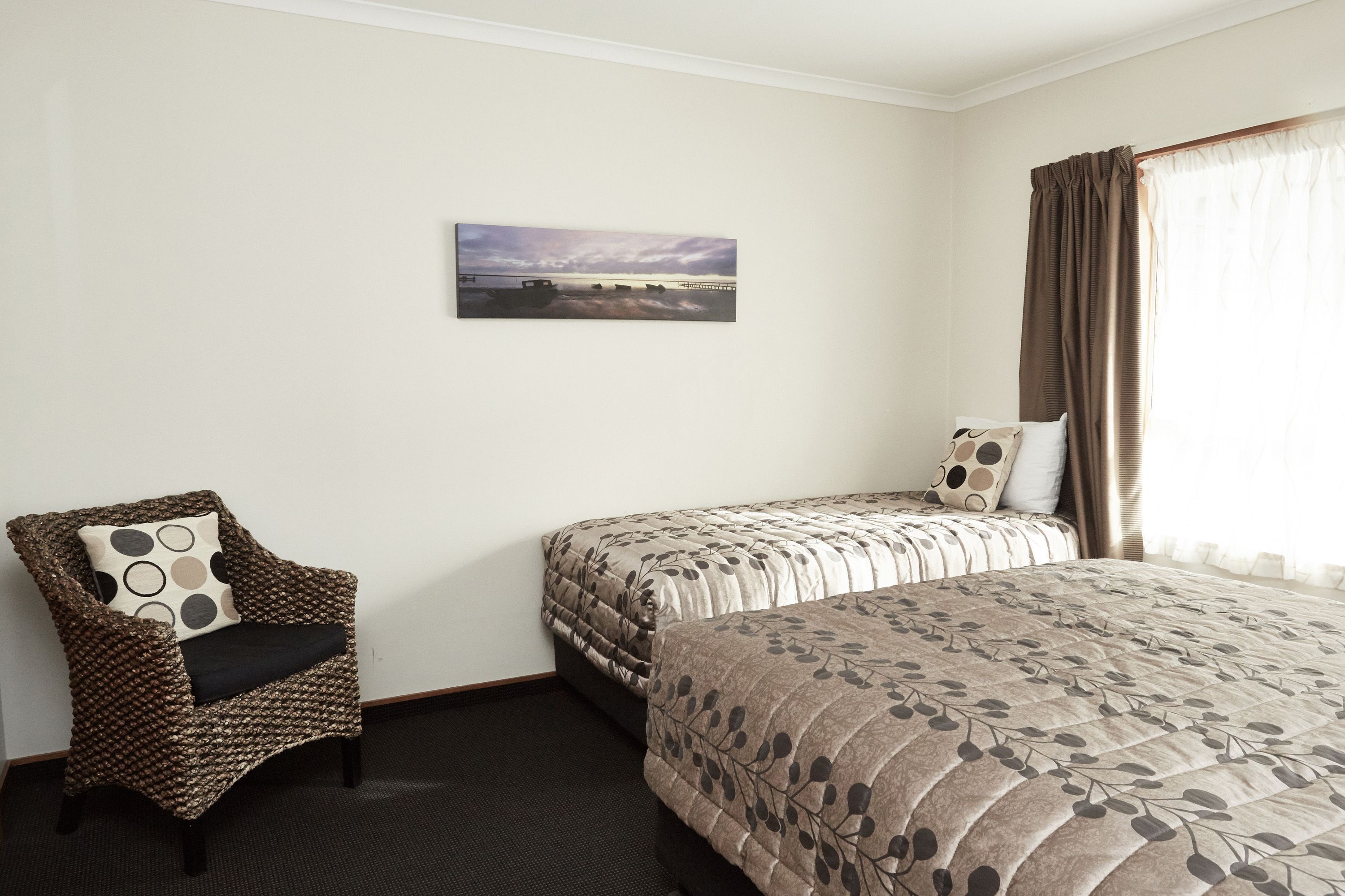 Quarto de hotel com cama, uma cadeira e um quadro na parede.