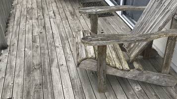 Um deck de madeira com duas cadeiras Adirondack e um vaso de planta.
