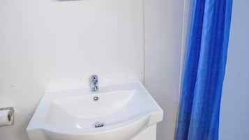 Casa de banho com lavatório branco, espelho e cortina de chuveiro azul.