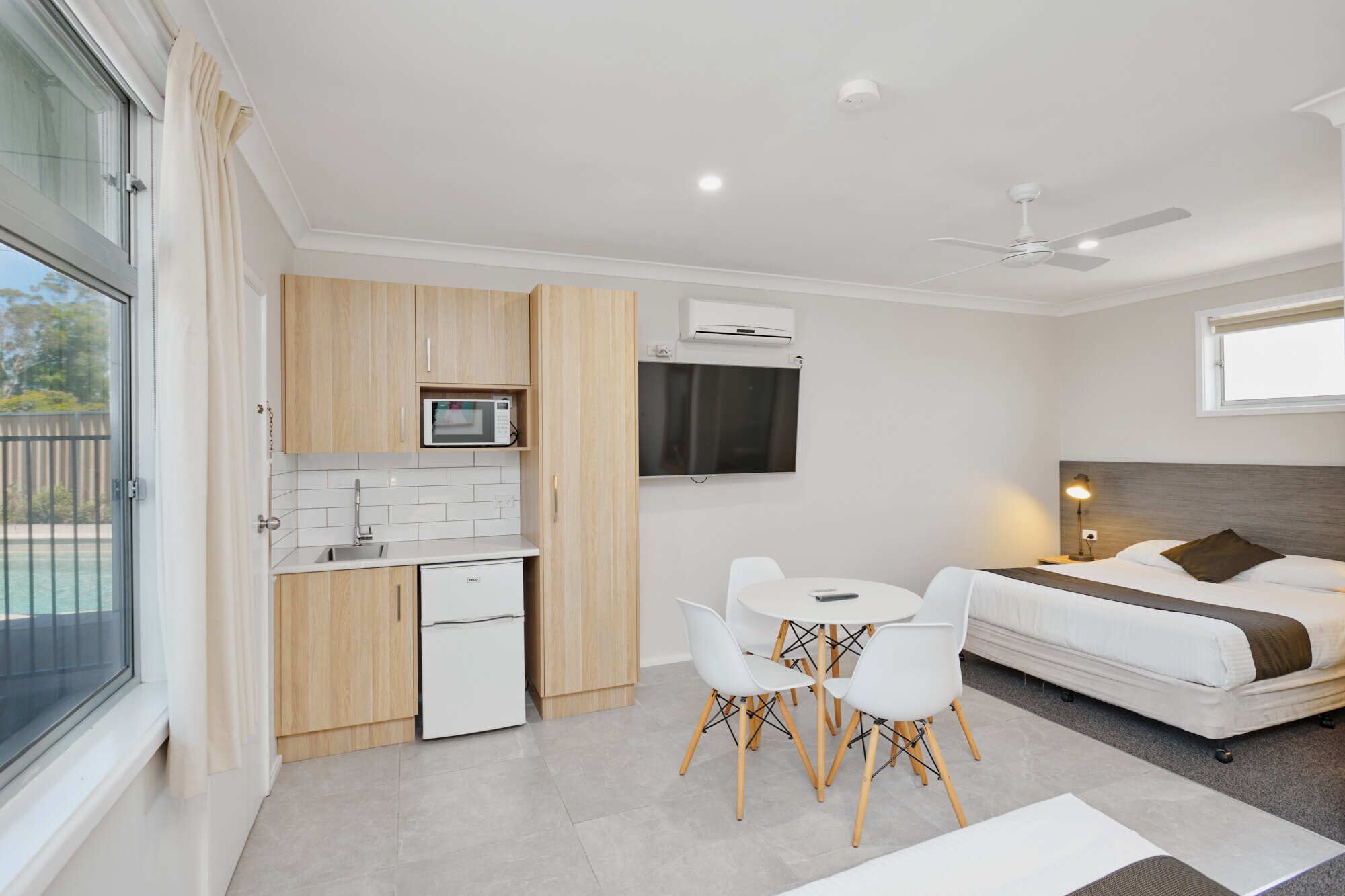 Quarto de hotel compacto com cozinha compacta, área de refeições e cama.