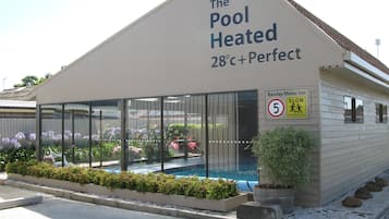 Um edifício com a placa "The Pool Heated 28°C + Perfect" e uma placa indicando "Barclay Motor Inn", além de uma placa de limite de velocidade de "5".