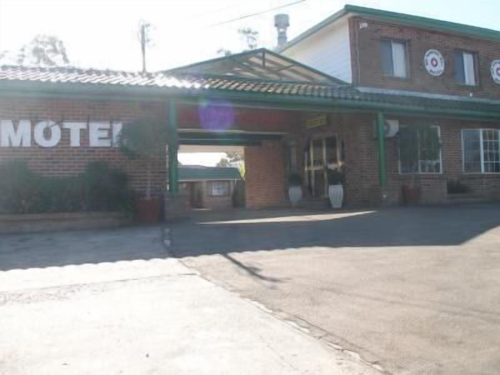 Um motel com fachada de tijolos, área de estacionamento coberta e entrada visível.