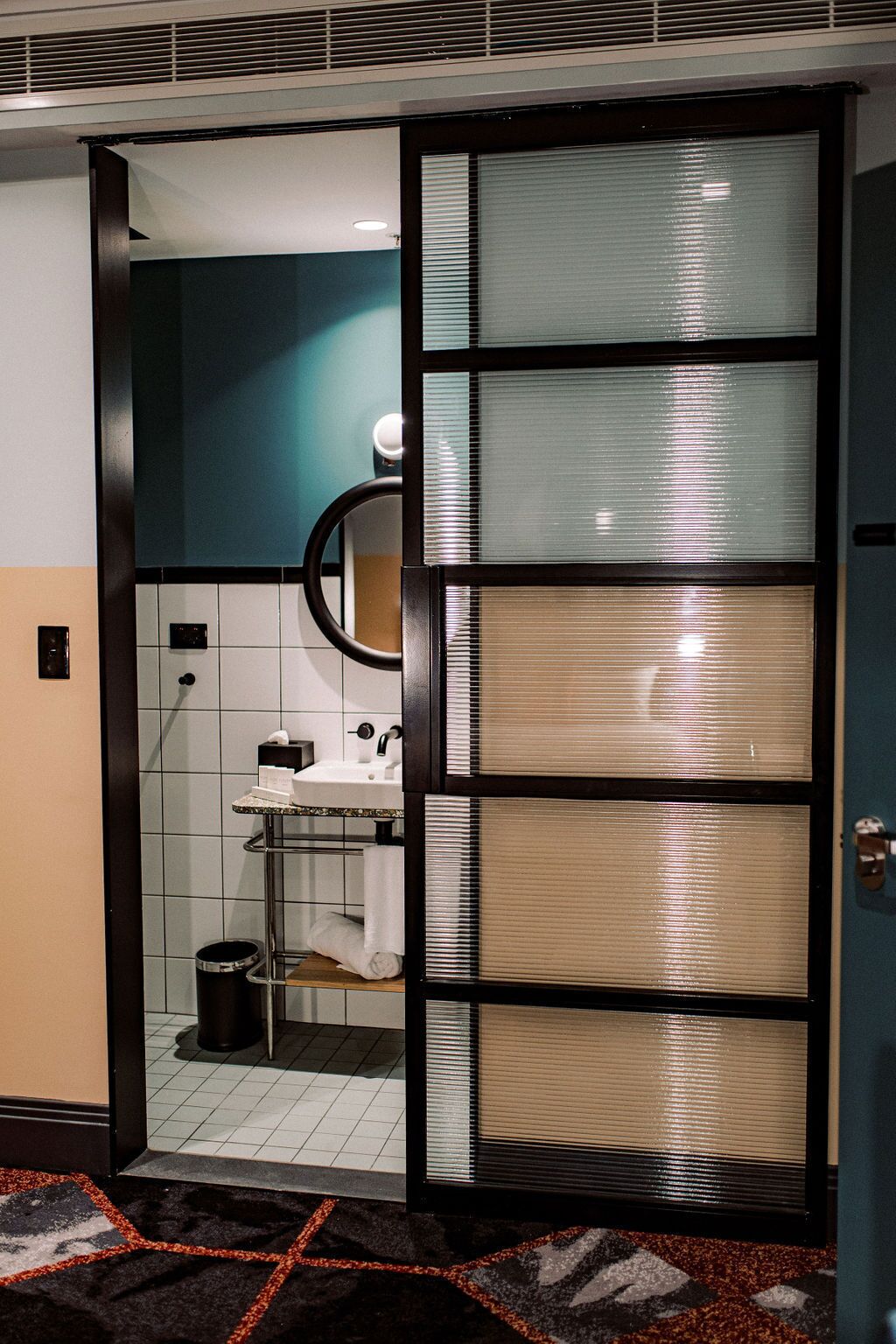 Uma casa de banho com lavatório, espelho e porta-toalhas.