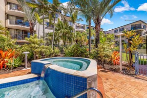 Um hotel com piscina, rodeado por palmeiras e plantas tropicais.