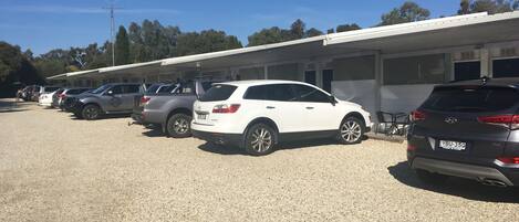 Um estacionamento com vários carros estacionados em frente a um edifício com várias garagens.