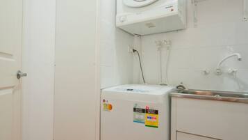 Uma lavanderia compacta com máquina de lavar, secadora e pia.