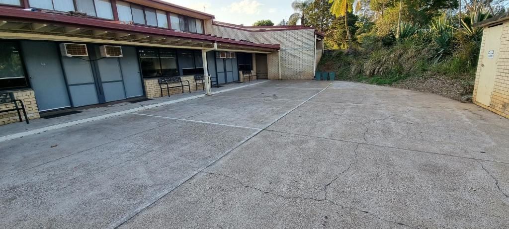 Um edifício com área externa coberta, aparelhos de ar condicionado e piso pavimentado.