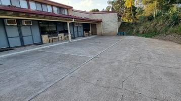 Um edifício com área externa coberta, aparelhos de ar condicionado e piso pavimentado.
