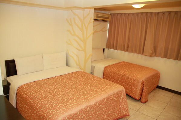 Quarto de hotel com duas camas, uma janela com cortinas e um aparelho de ar condicionado na parede.