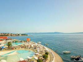 Um resort à beira-mar com uma grande piscina, espreguiçadeiras e barcos na água.