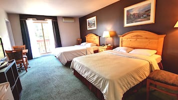 Quarto de hotel com duas camas, uma escrivaninha, uma cadeira, um abajur e um quadro na parede.