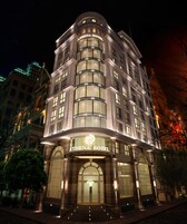 Um hotel com vários andares, uma entrada imponente, grandes janelas e fachada bem iluminada.