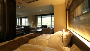 Quarto de hotel com cama, escrivaninha, cadeira e sofá.