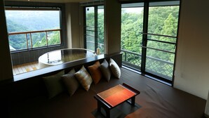 Quarto com uma grande janela, um banco de madeira e um espaço de estar com assentos acolchoados.