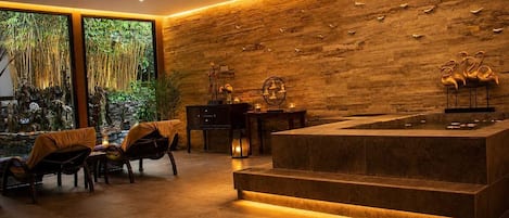 Um interior moderno com parede de pedra, balcão de recepção de madeira e área de estar com cadeiras.