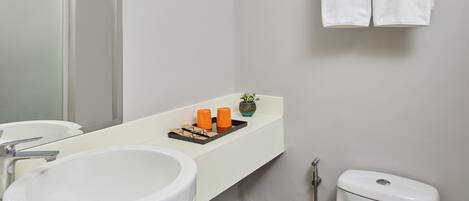 Um banheiro com pia branca, vaso sanitário e porta-toalhas com duas toalhas.
