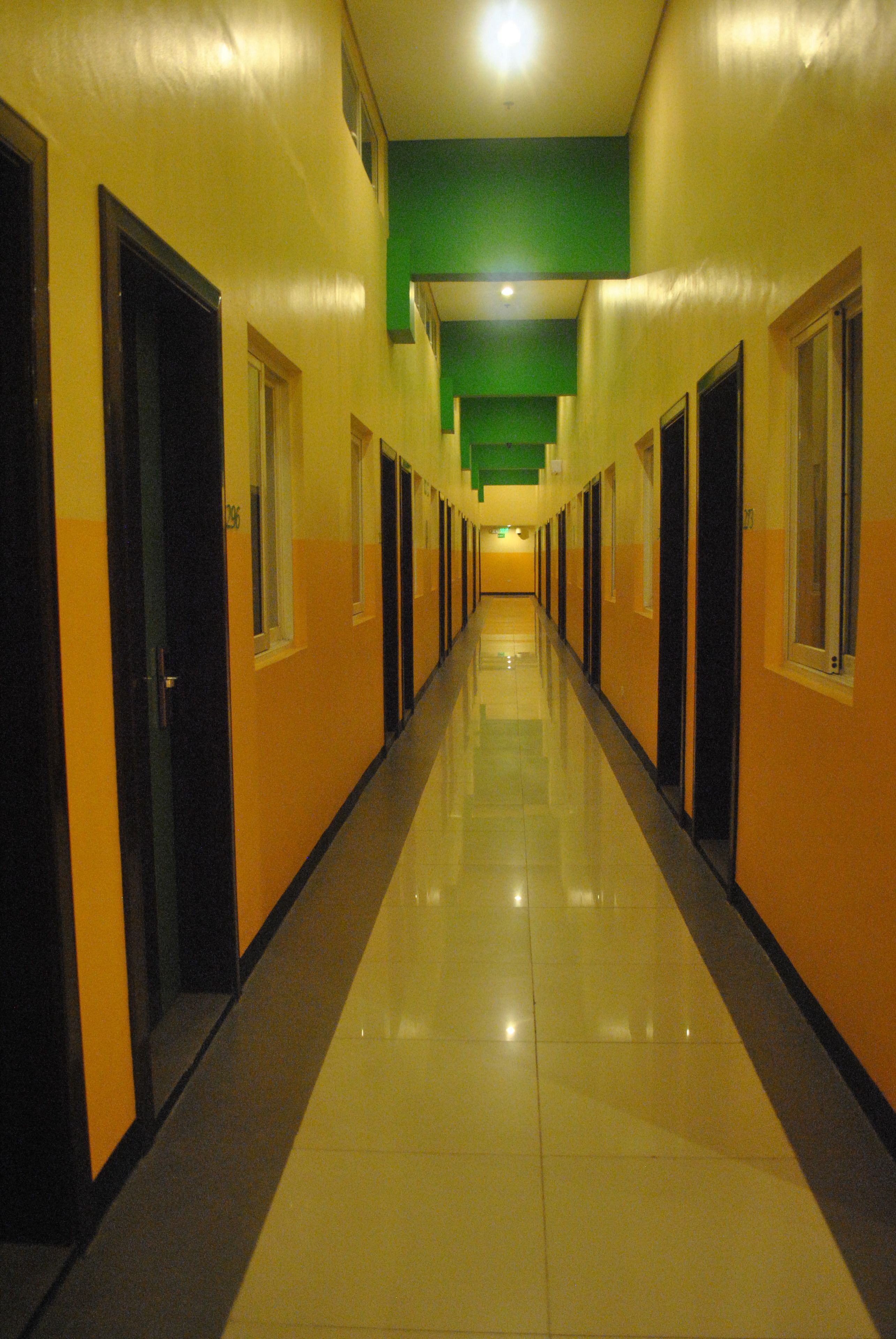 Um corredor comprido e estreito, com portas de ambos os lados, que dá acesso a quartos individuais.