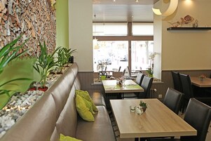 Um restaurante com mesa de madeira, um banco acolchoado e plantas em vasos.