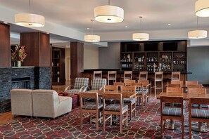 Um saguão de hotel com área de bar, sofás e lareira.