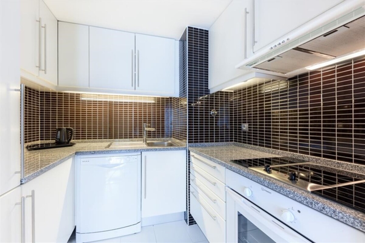 Cozinha moderna com armários brancos, lava-louças embutida, fogão e micro-ondas.