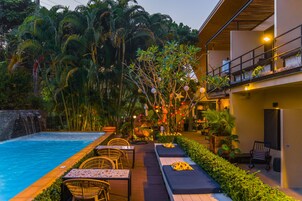 Uma área de piscina com cascata, assentos de descanso e uma mesa de jantar.