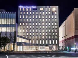 O Hotel Daiwa Roynet com fachada moderna, grandes janelas e área de entrada bem iluminada.