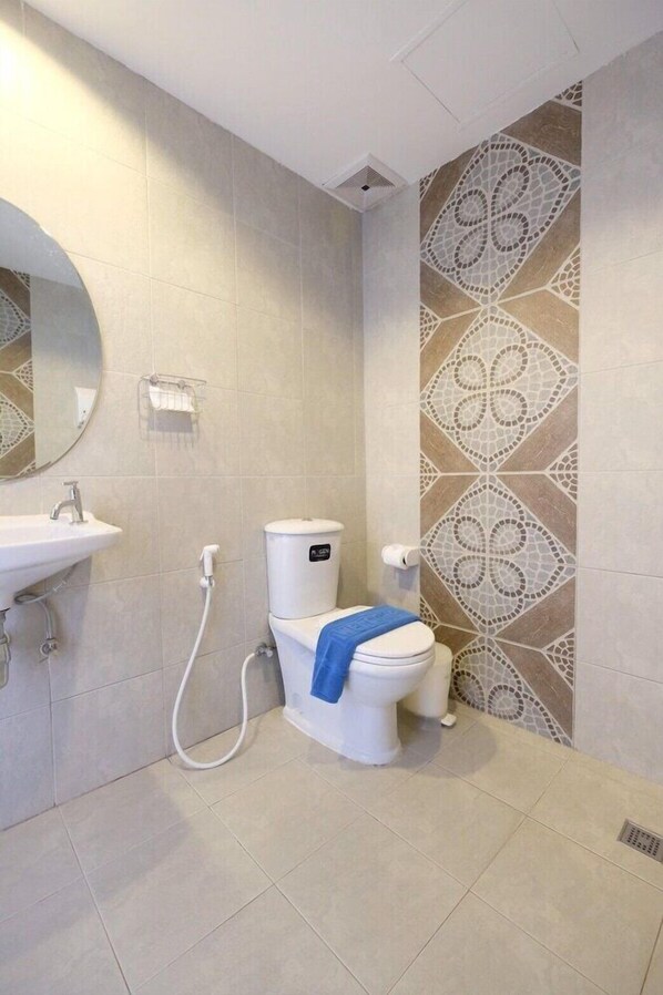 Casa de banho com sanita, lavatório e parede decorativa em azulejos.