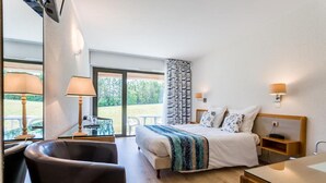 Quarto de hotel com cama, mesa de cabeceira, abajur e vista para o exterior.
