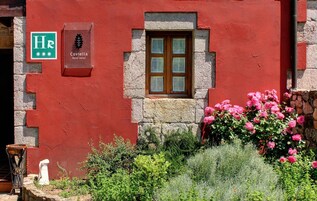 Um edifício vermelho com uma placa indicando 'Coviella hotel rural'.