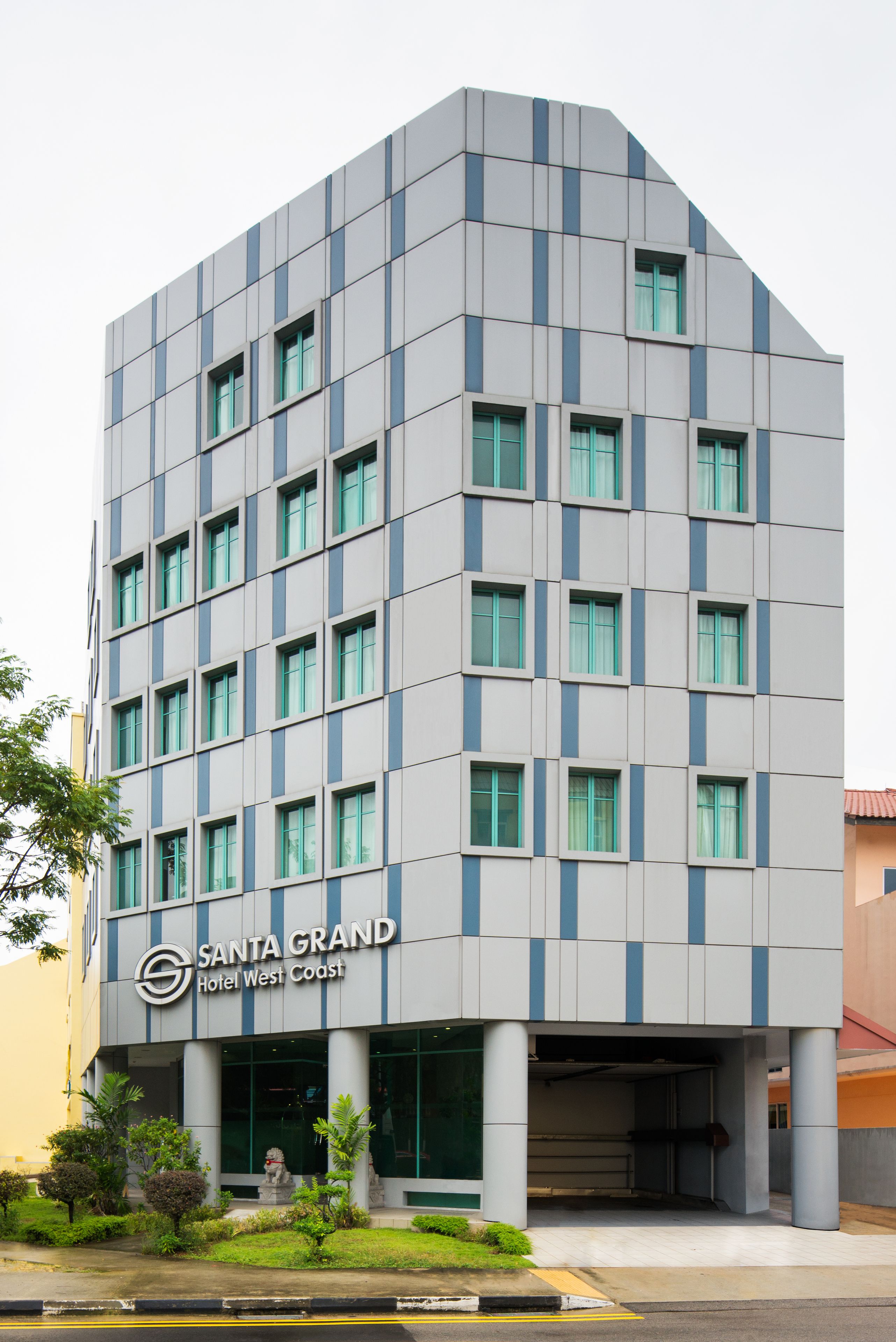 Um hotel moderno com uma fachada de janelas em grade e uma placa com a inscrição 'Santa Grand Hotel West Coast'.