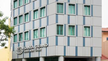 Um hotel moderno com uma fachada de janelas em grade e uma placa com a inscrição 'Santa Grand Hotel West Coast'.