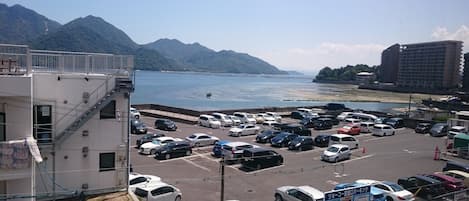 Um estacionamento com vários carros, um edifício com escadas e montanhas ao fundo.