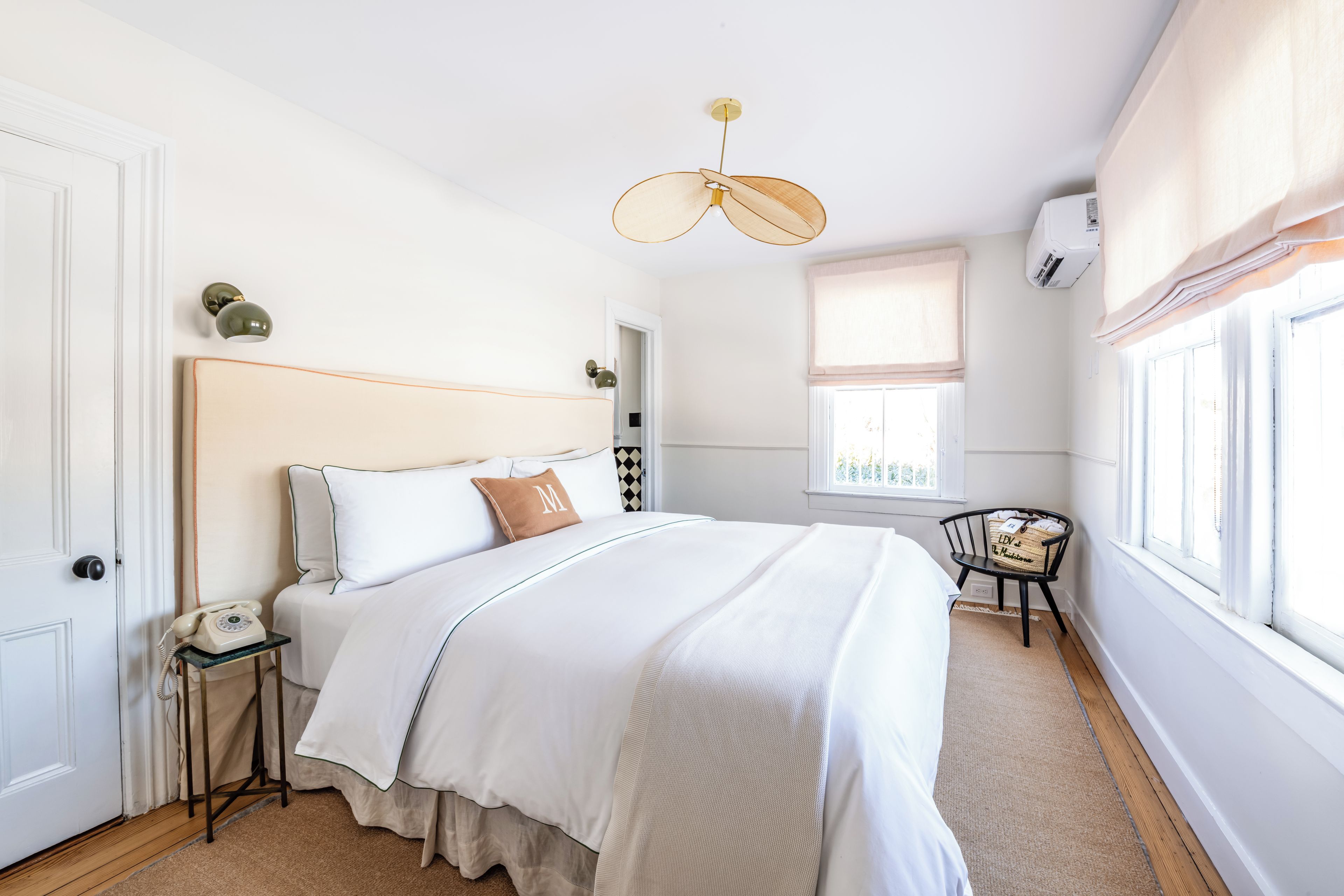 Quarto com cama, mesa de cabeceira, abajur e janela com vista.