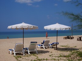 Na praia, praia de areia branca, espreguiçadeiras, guarda-sóis de praia 