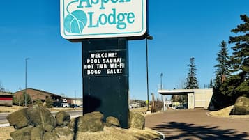 Placa do Aspen Lodge com serviços listados: piscina, sauna, banheira de hidromassagem e promoção compre um, leve outro.