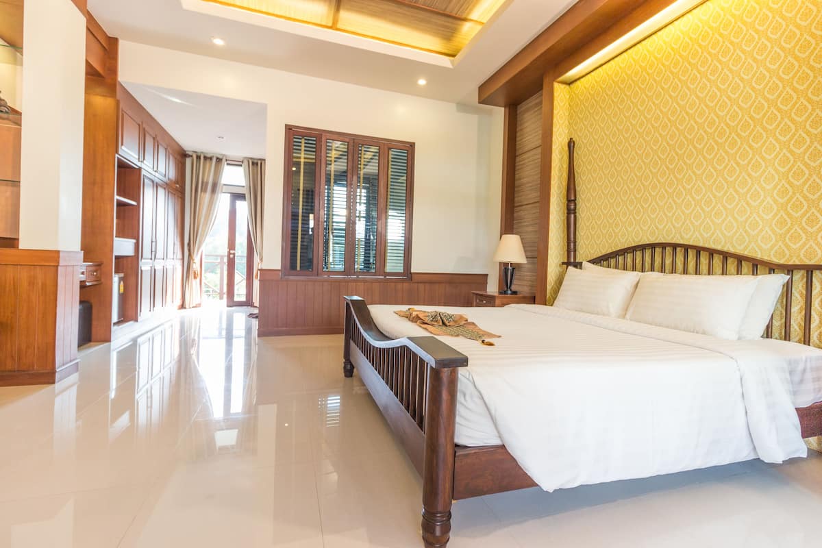Um quarto espaçoso com uma cama grande, cabeceira de madeira e mesa de cabeceira.