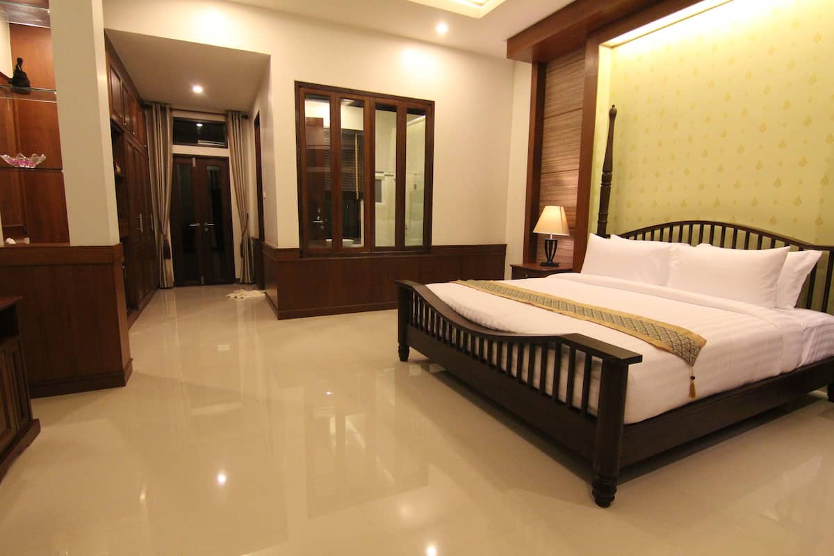 Quarto de hotel com uma cama grande, mesa de cabeceira, espelho e guarda-roupa.