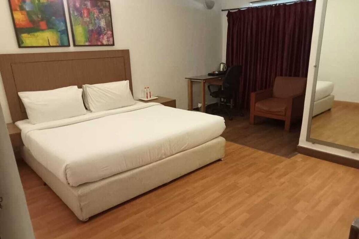 Quarto de hotel com uma cama grande, uma mesa, uma cadeira e um espelho.
