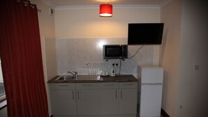 Cozinha compacta com micro-ondas, pia e pequena geladeira.