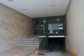 Interior moderno com escadaria de mármore, guarda-corpos de vidro e iluminação embutida.