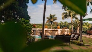 Área de piscina com espreguiçadeiras e muro de pedra.