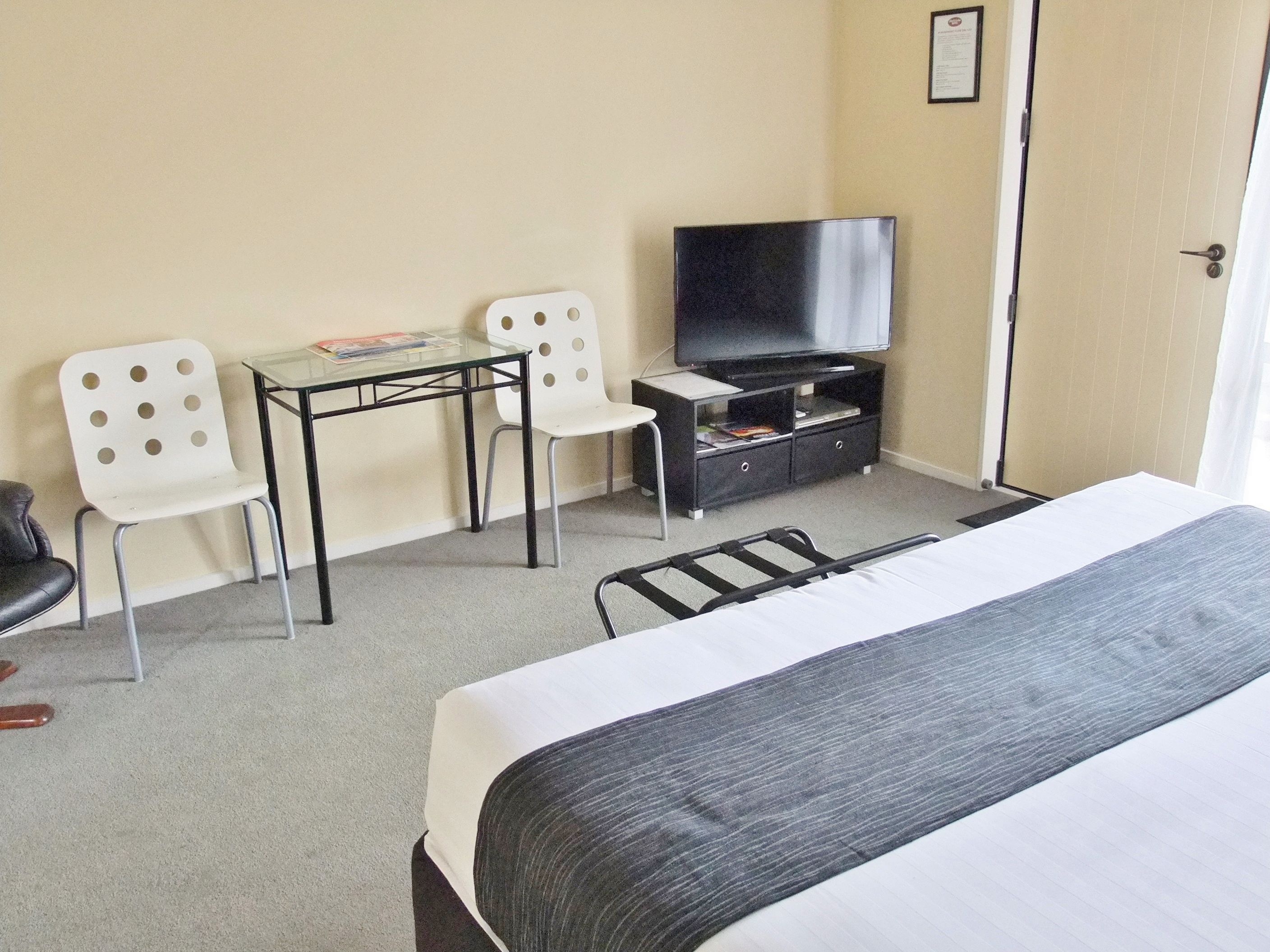 Quarto de hotel com cama, televisão, secretária com cadeiras e uma pequena mesa.