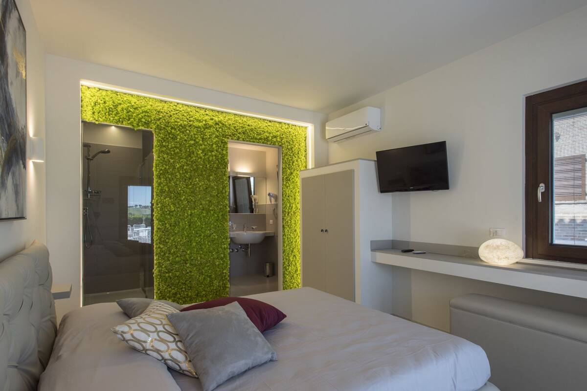 Quarto moderno com uma cama, uma TV e uma parede verde.