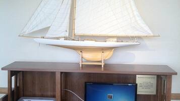 Uma mesa de madeira com um computador, uma impressora e uma réplica de veleiro.