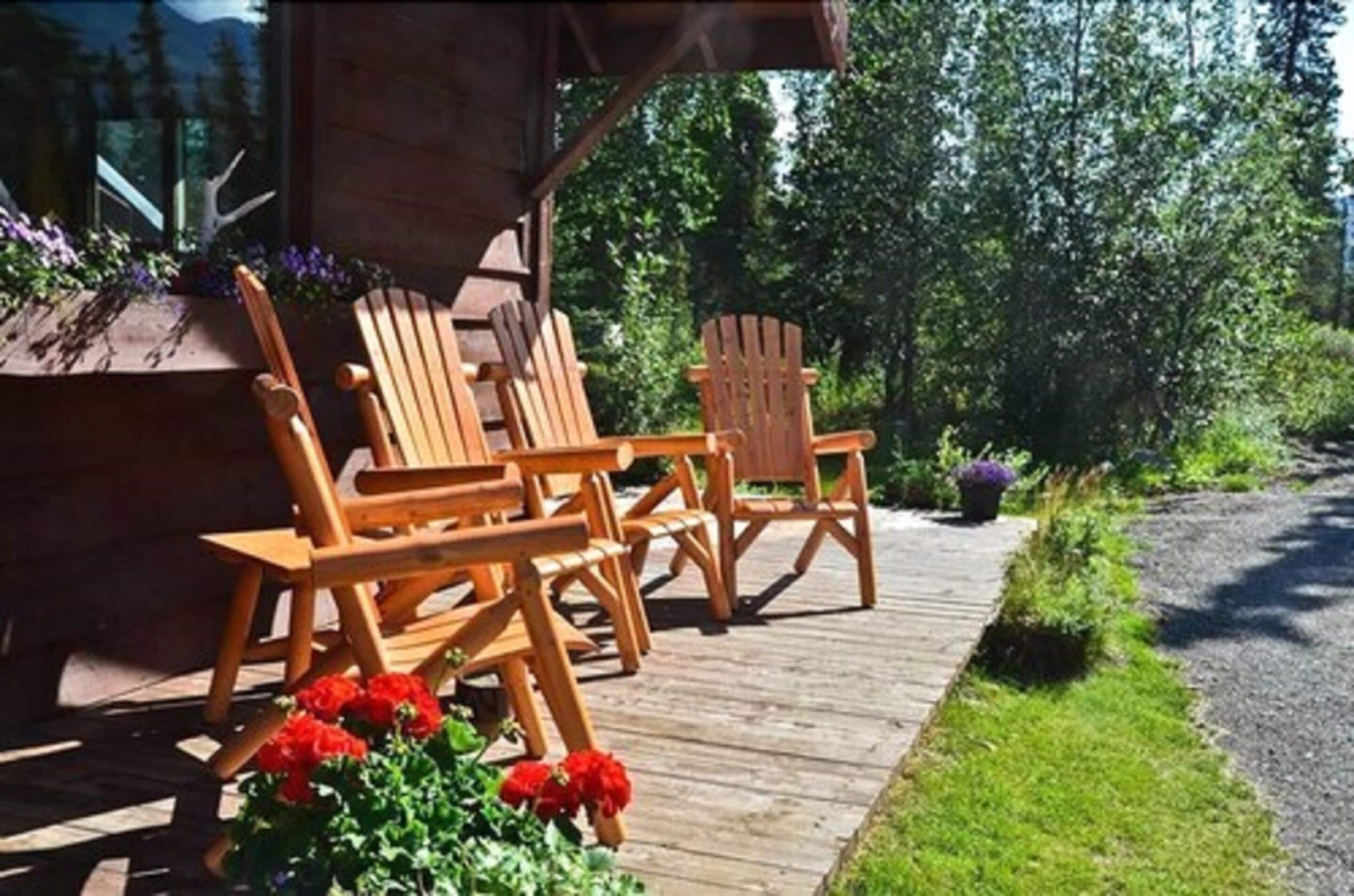 Um deck de madeira com cadeiras Adirondack e um vaso de planta.