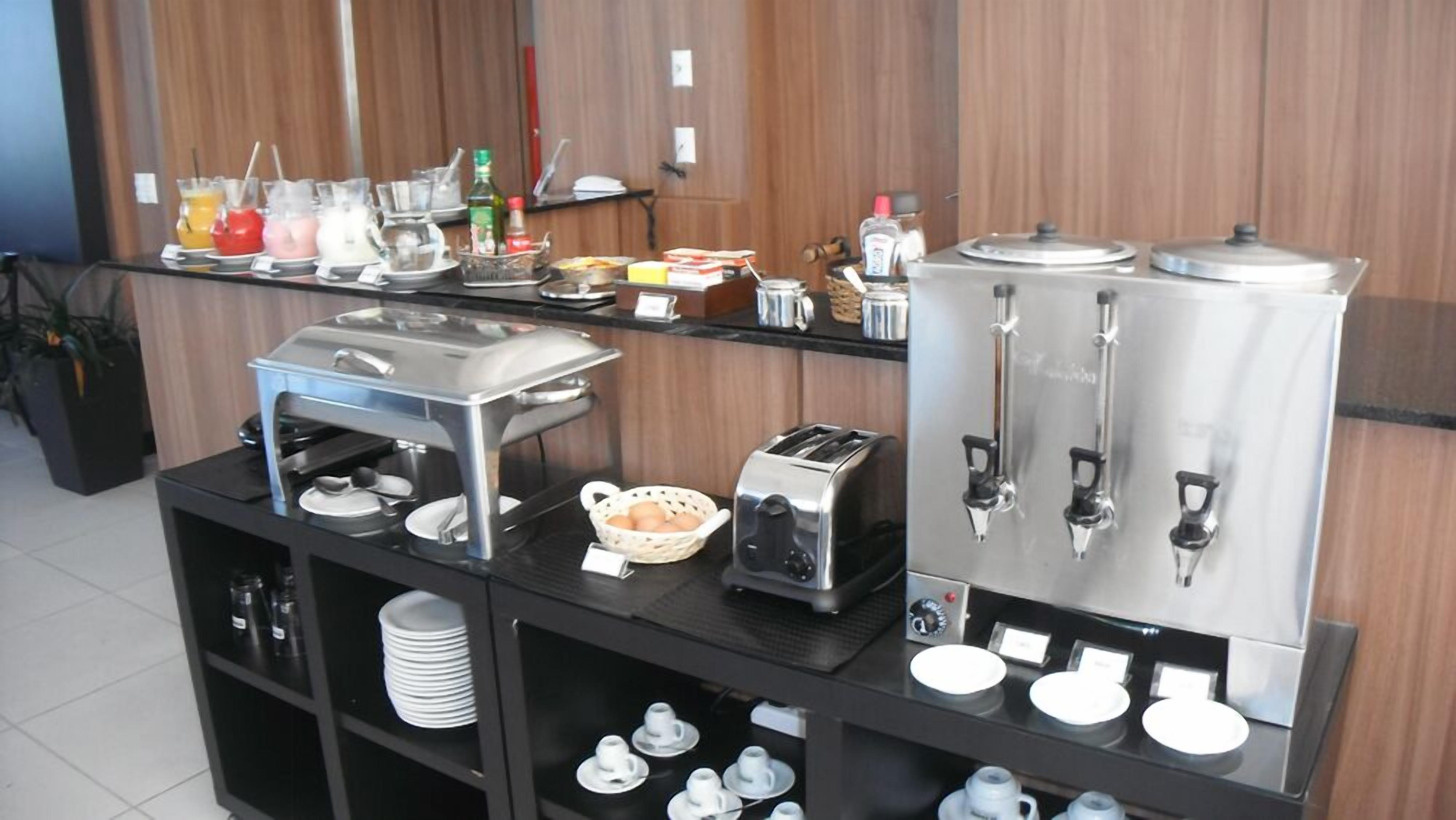 Disposição de buffet com estação de café, torradeira e diversos alimentos.