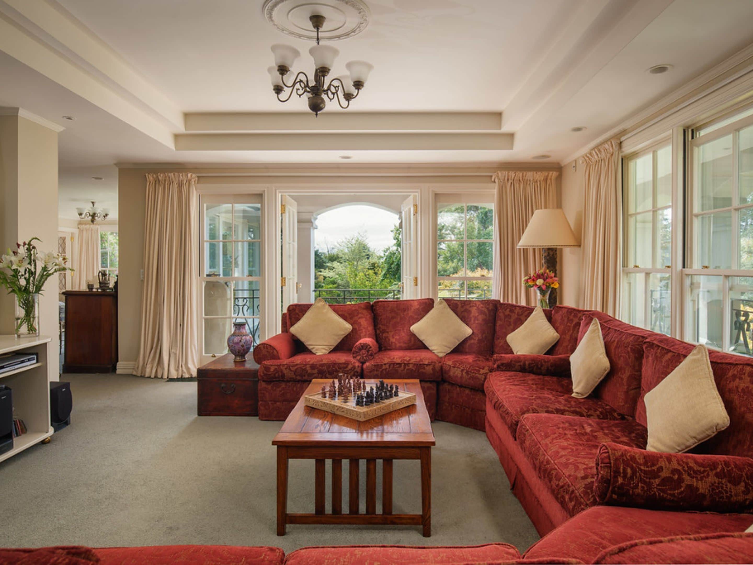 Uma sala de estar ampla com um sofá vermelho, uma mesa de centro de madeira e um tabuleiro de xadrez.