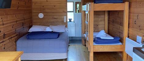 Uma cabana acolhedora com cama no mezanino, sofá-cama, mesa de jantar e cozinha compacta.