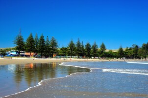 Na praia, areia branca, espreguiçadeiras, prática de vôlei de praia 
