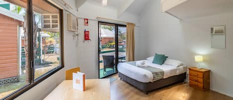 Quarto com cama, mesa de cabeceira e janela.